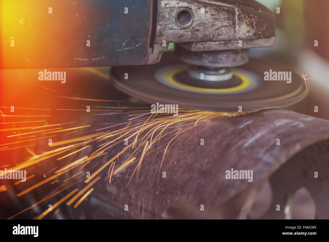 Worker grinding steel pipe, man using grinder to work on piece of metal ...