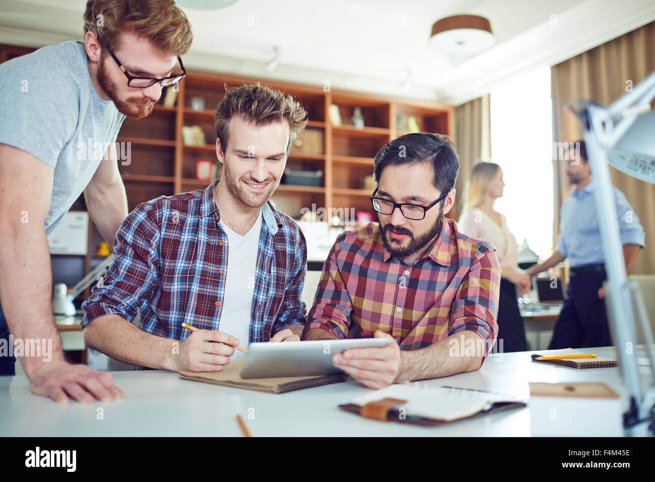 Three businessmen with touchpad checking data Stock Photo - Alamy
