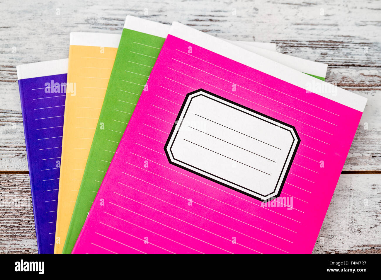 Colorful notebooks with name label on cover on white wooden background ...