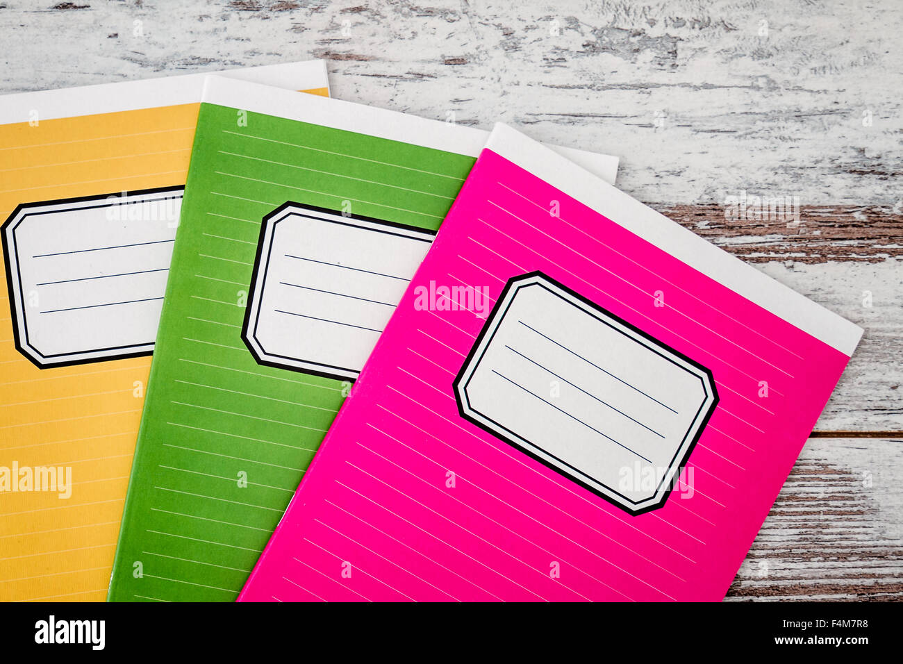 Colorful notebooks with name label on cover on white wooden background ...