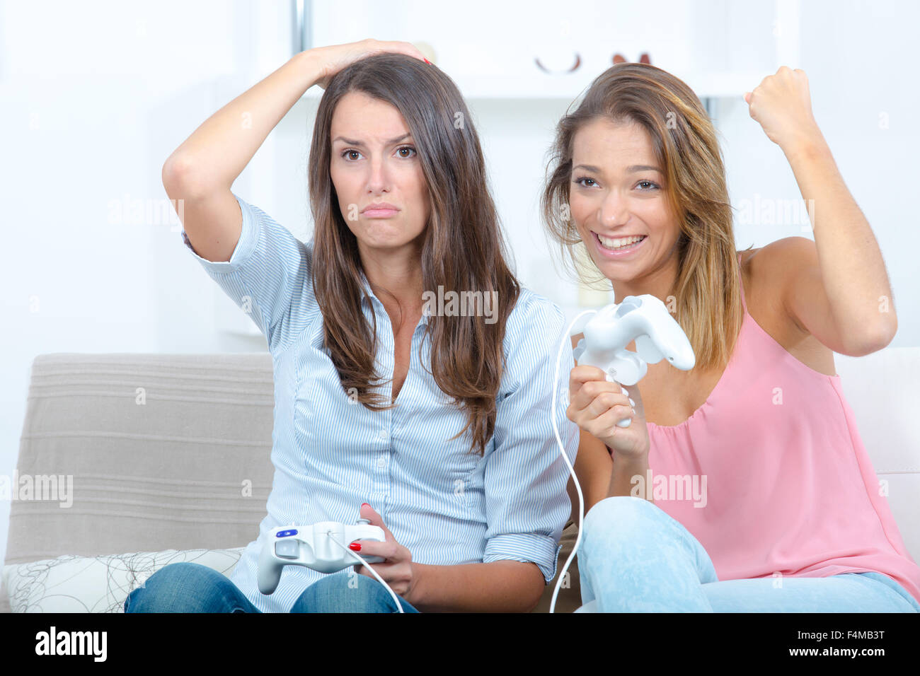 Two female friend playing on a games console Stock Photo - Alamy