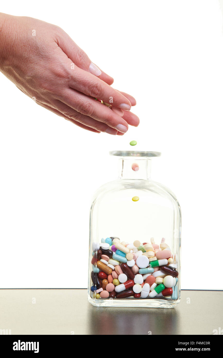 Hand filling colorful pills in glass container Stock Photo - Alamy