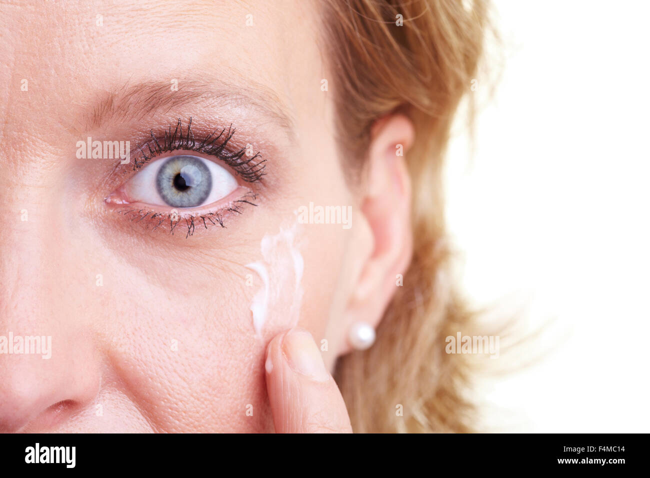 Woman applying face lotion to her cheeks Stock Photo - Alamy