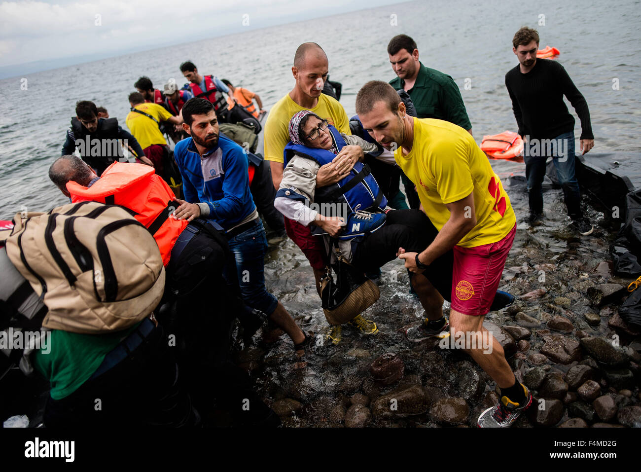 A refugee is carried out of a rubber raft by two helpers after crossing ...