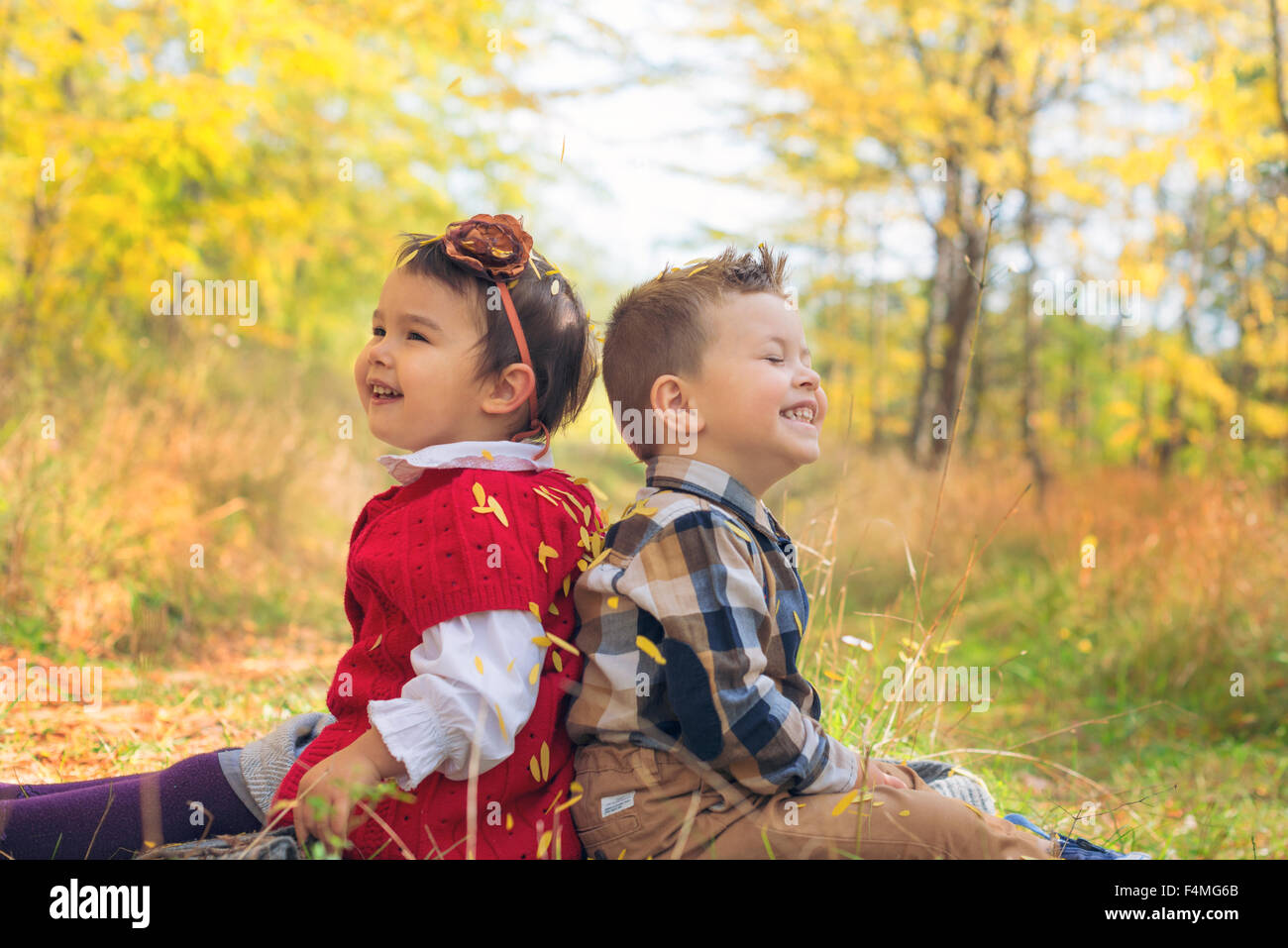 Adorable little kids with autumn leaves in the beauty park, sitting ...