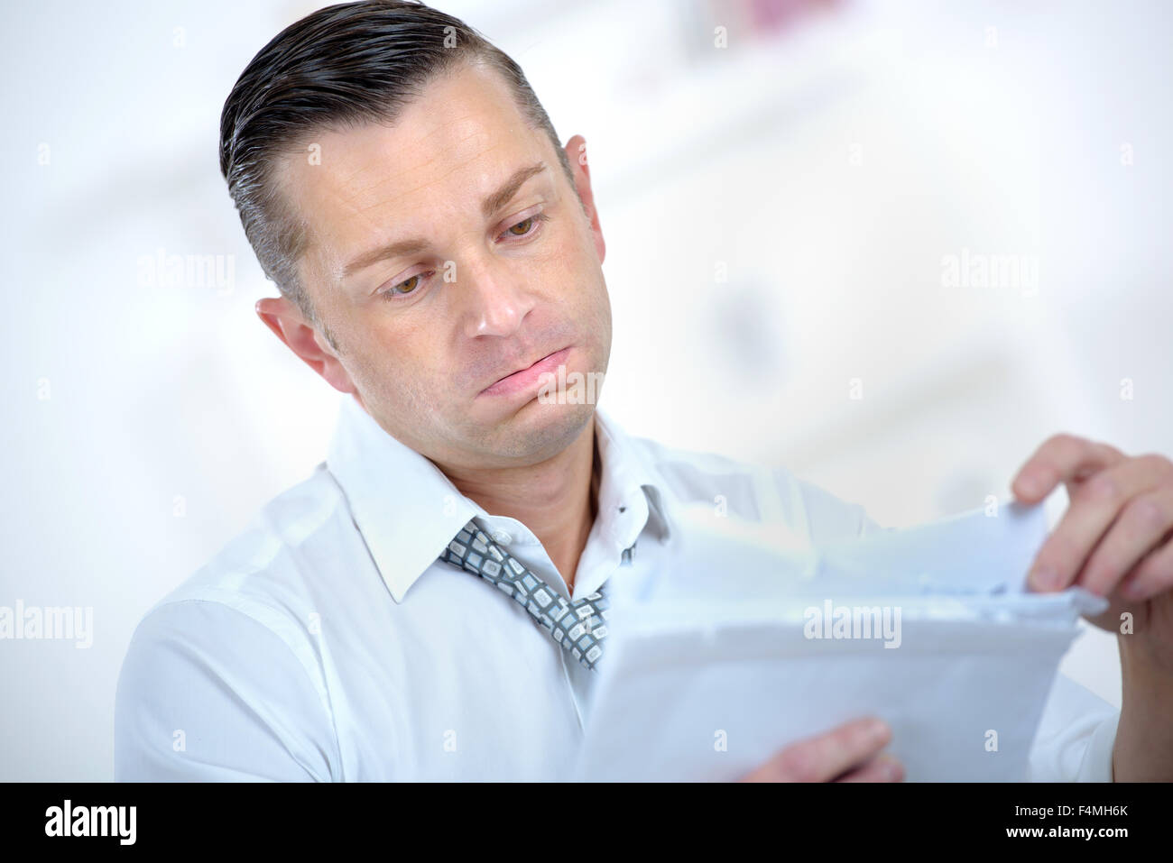 Depressed man looking at paperwork Stock Photo - Alamy