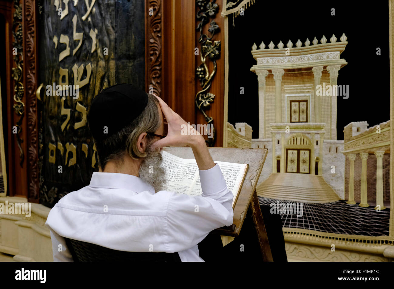 A Jewish worshiper prays next to a Torah Ark closet which contains the ...