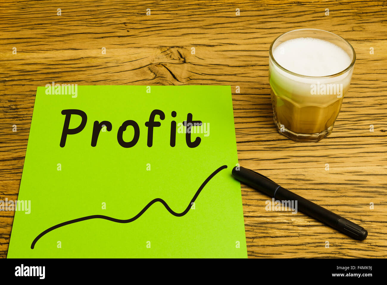 Profit written on green paper with graph. Marker and coffee on desk ...