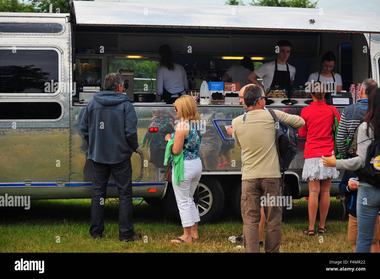 Customers queue to get food from an American style fast food trailer at ...