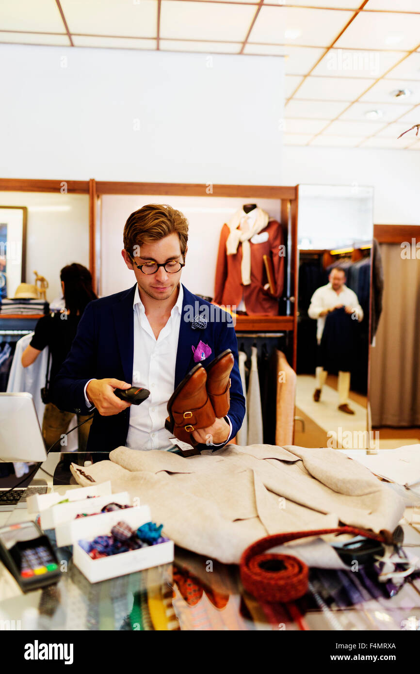 Cashier using bar code reader on shoes at checkout counter in clothing ...