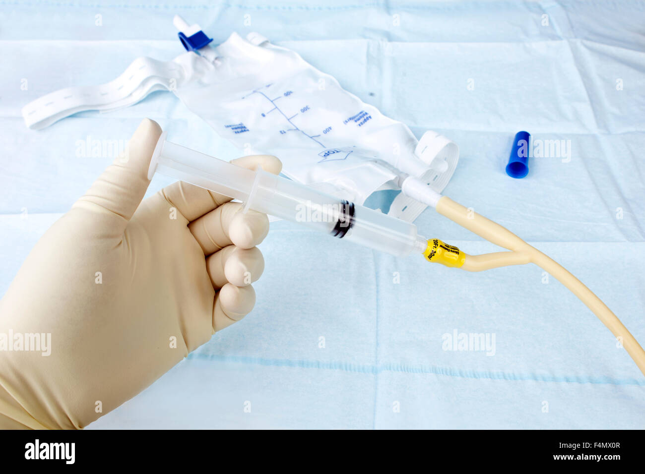 Nurse inflates urinary catheter bulb with leg drainage bag on sterile ...