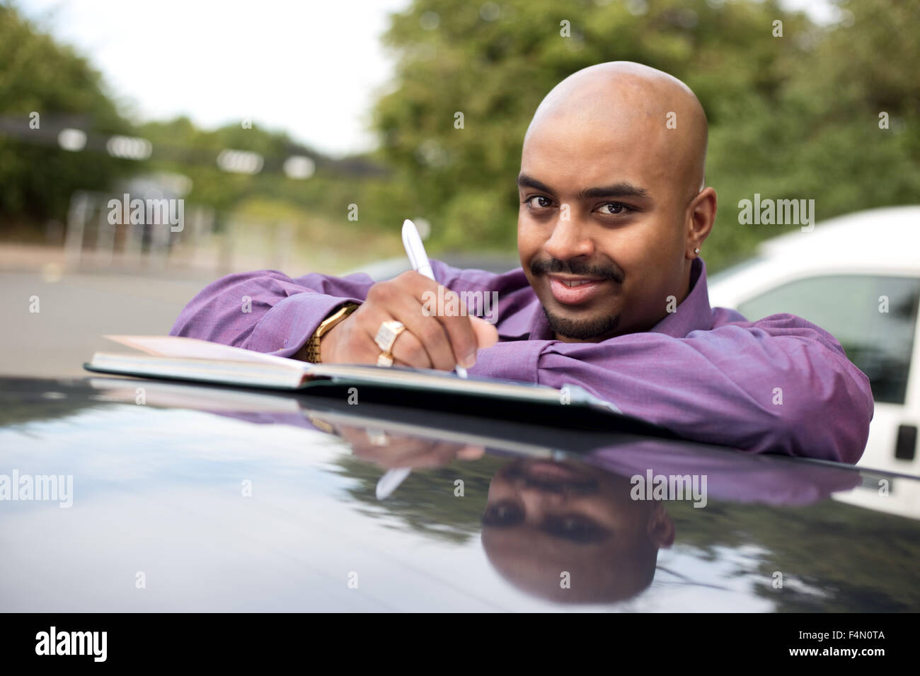 man writing in a notebook on top of his car Stock Photo - Alamy