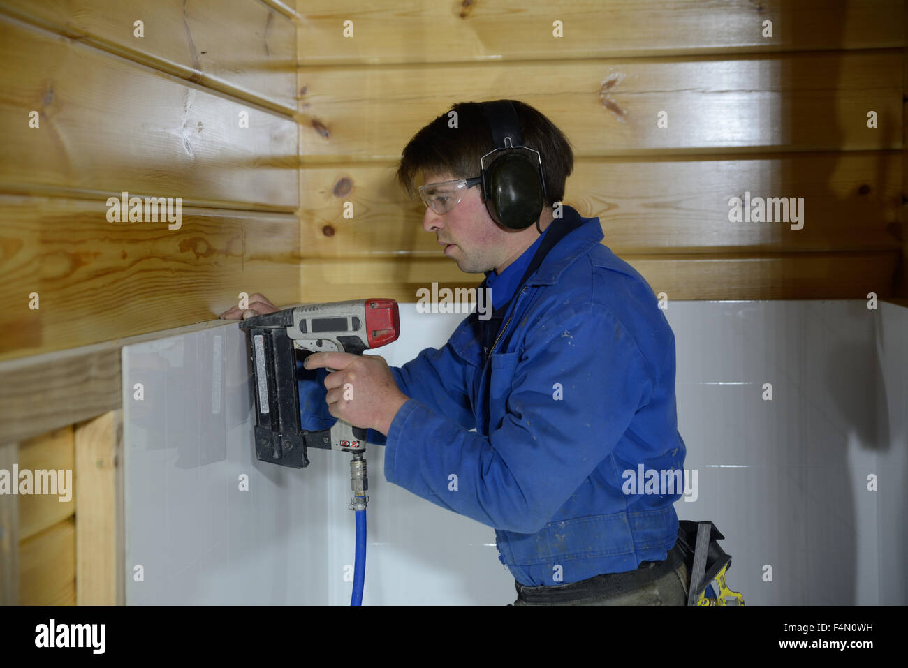 A builder staples off waterproof wall cladding in a bathroom Stock ...