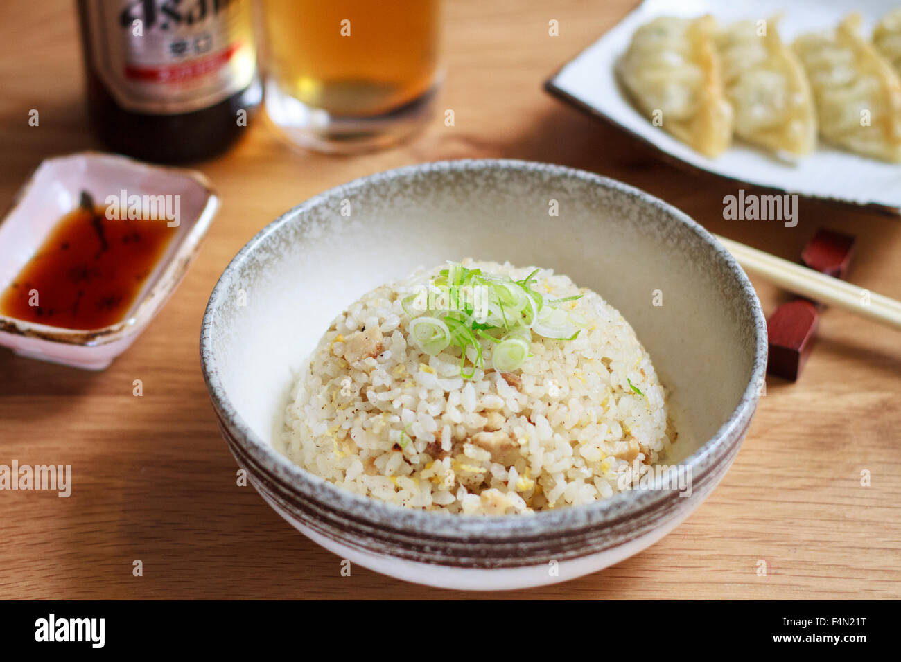 A bowl of Fried rice with Dumplings, Asahi beer and soy sauce in the ...