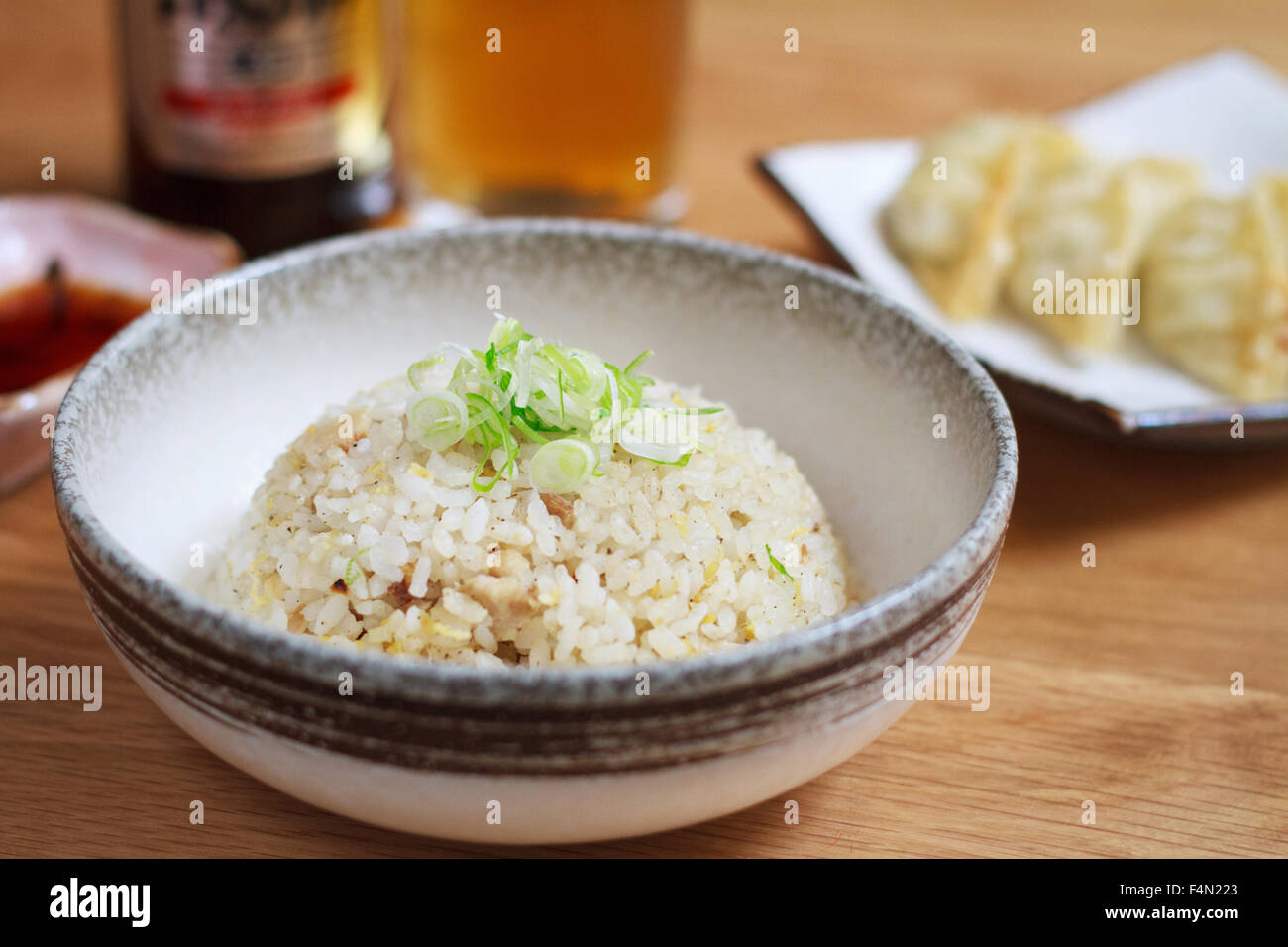 A bowl of Fried rice with Dumplings, Asahi beer and soy sauce in the ...