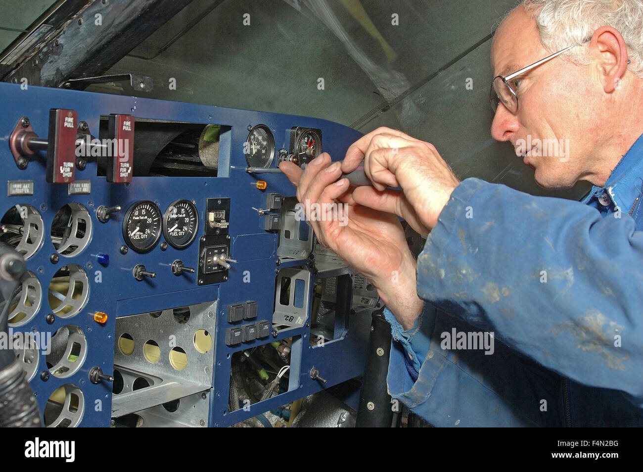 An aircraft engineer replaces the controls on the front console in the ...