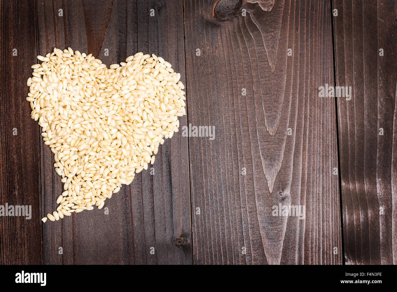 In the picture an heart formed by grains of rice on background of wood ...
