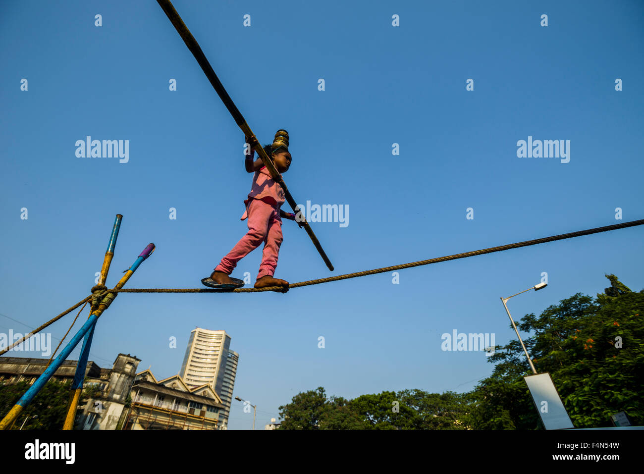A little girl is performing artistics on a rope strained between poles ...
