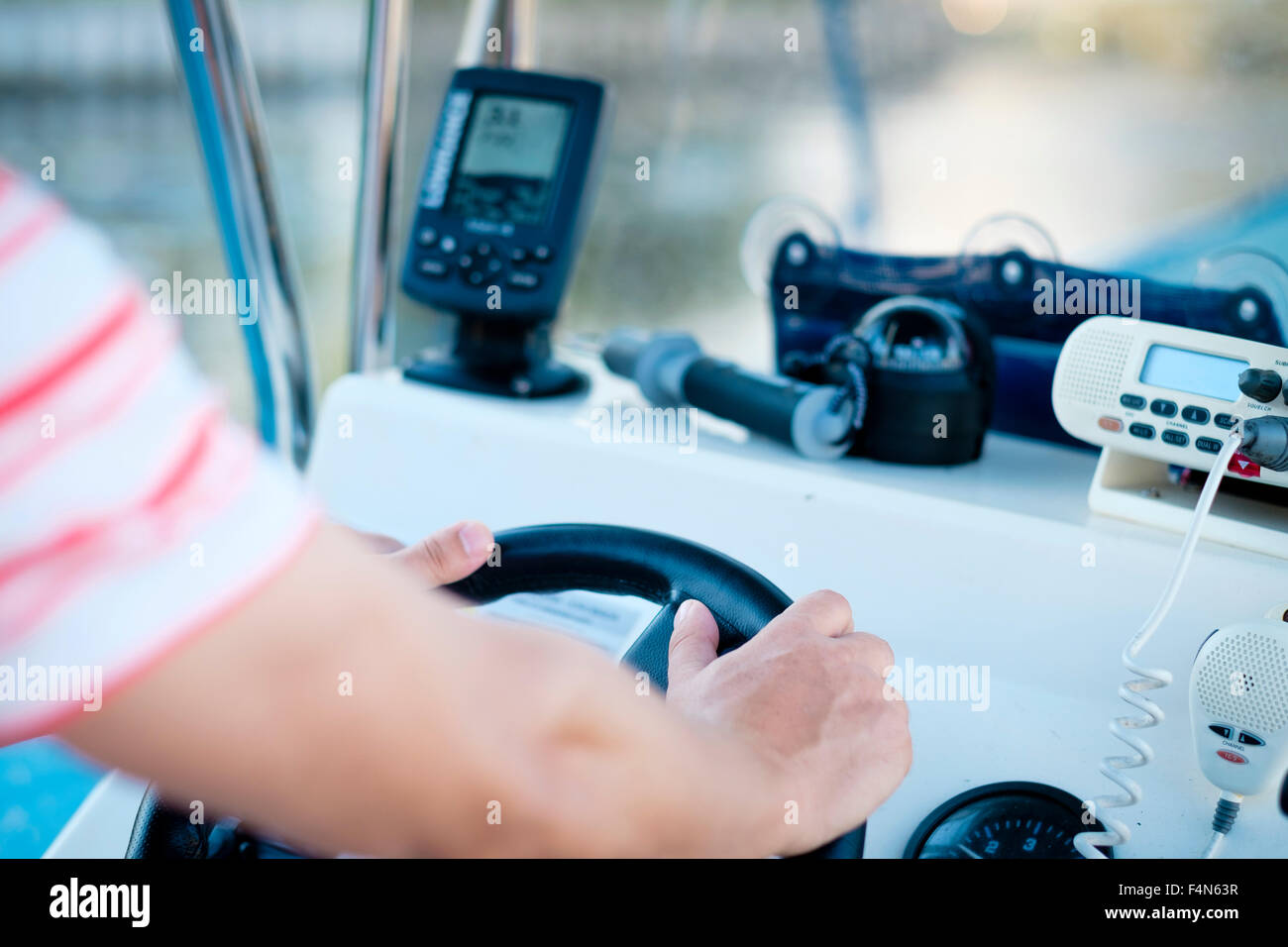 Hands at the steering wheel of a fishing boat with fish finder, GPS ...