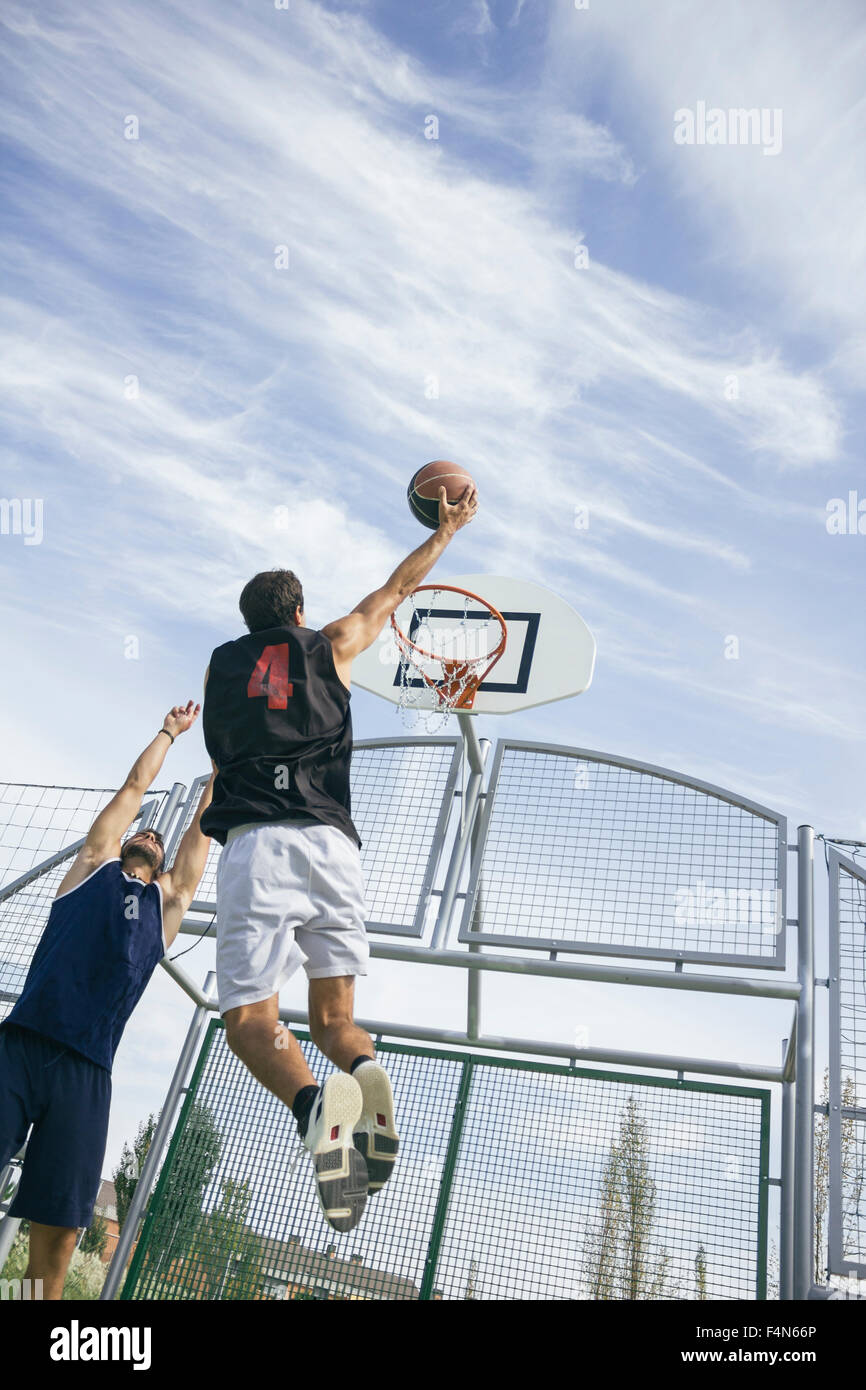 Young man playing basketball, dunking ball Stock Photo - Alamy