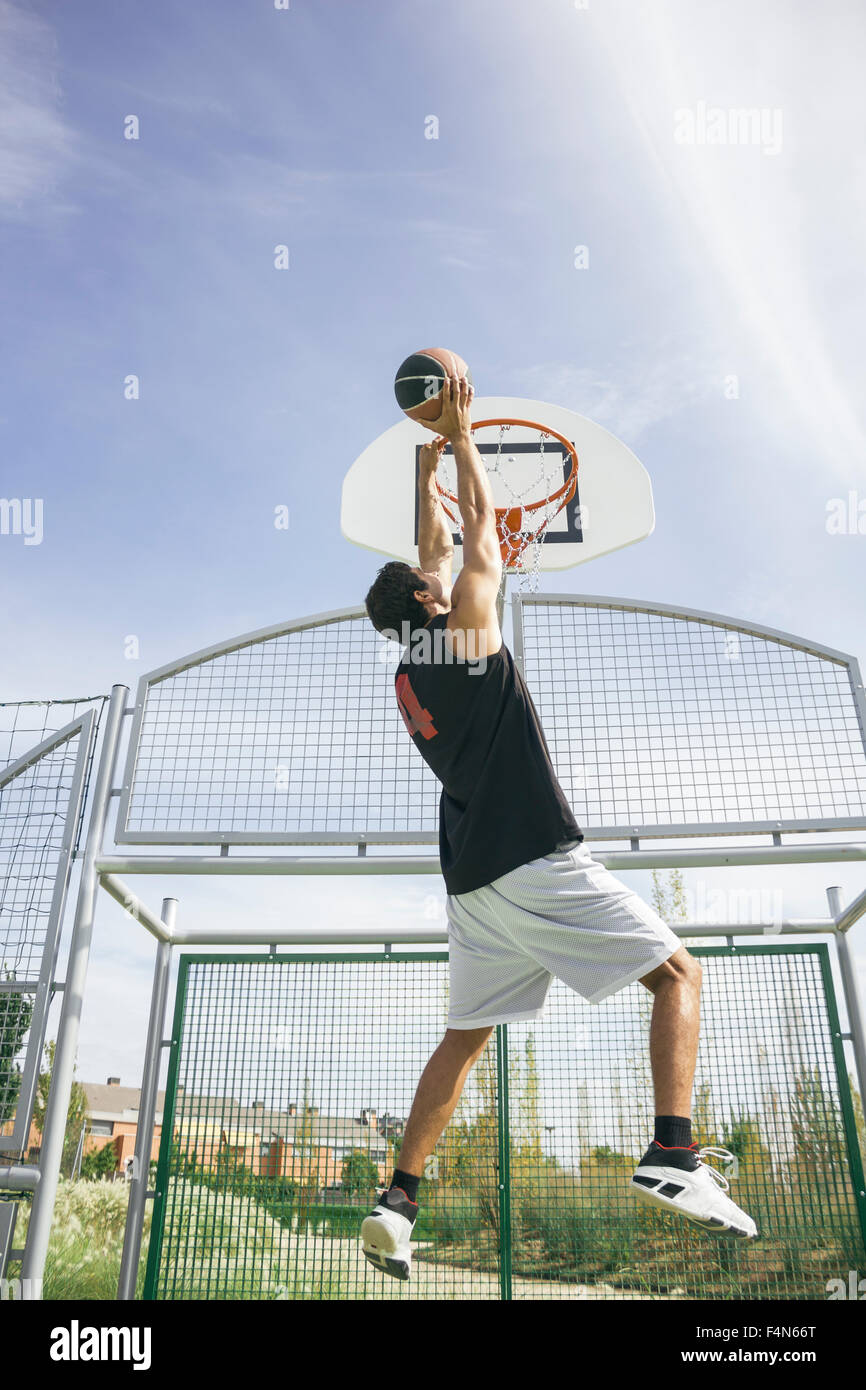 Young man playing basketball, dunking ball Stock Photo - Alamy
