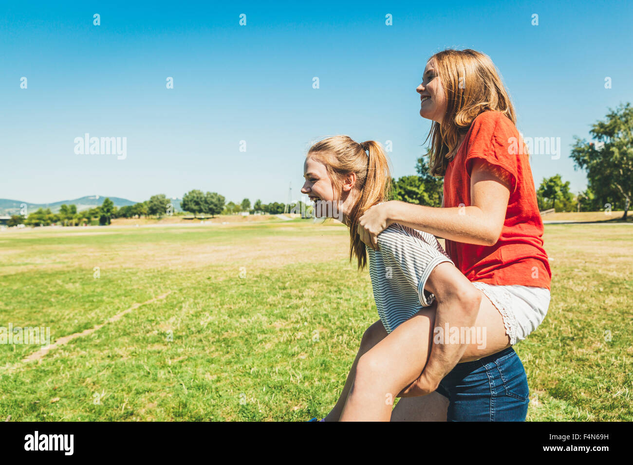 Carefree teenage girl carrying friend piggyback in park Stock Photo - Alamy