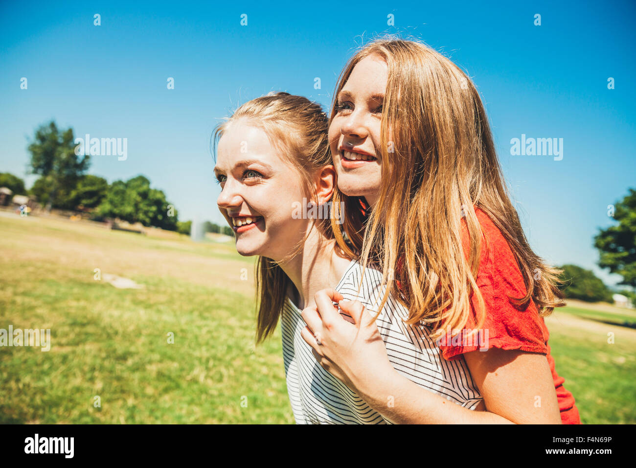 Teenage girl carrying friend piggyback in park Stock Photo - Alamy