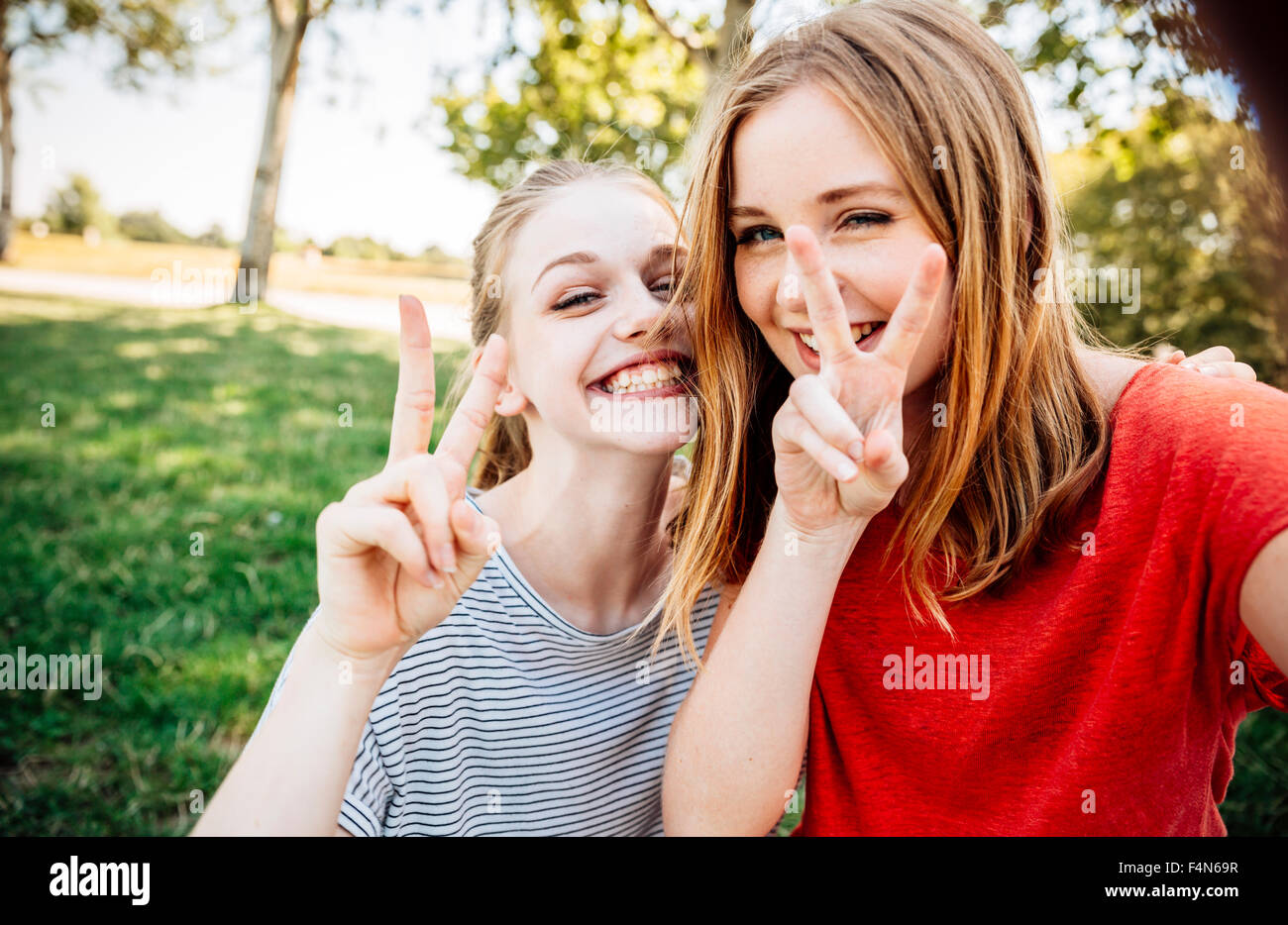 Two playful teenage girls making victory sign Stock Photo - Alamy