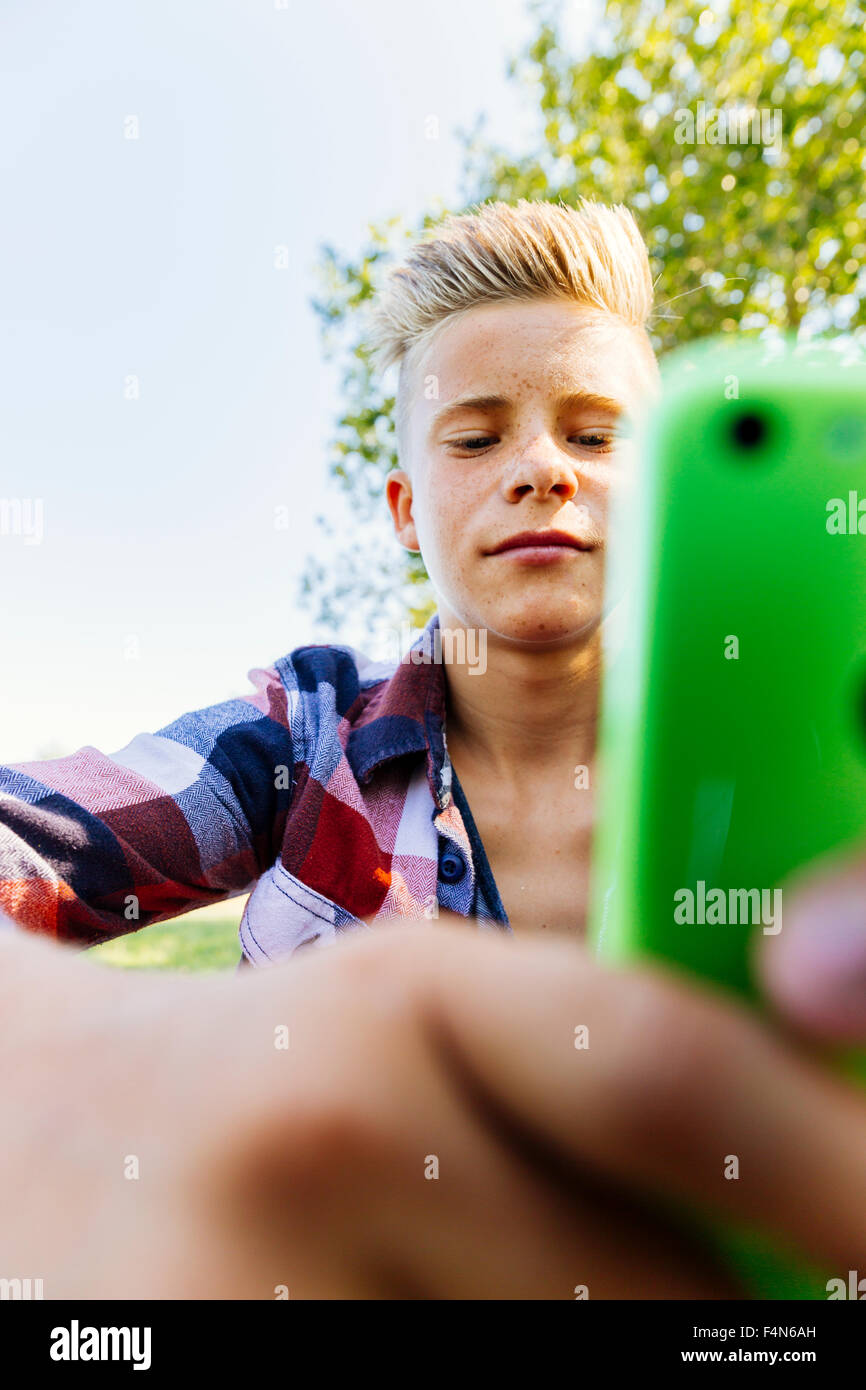 Teenage boy looking on smartphone outdoors Stock Photo - Alamy