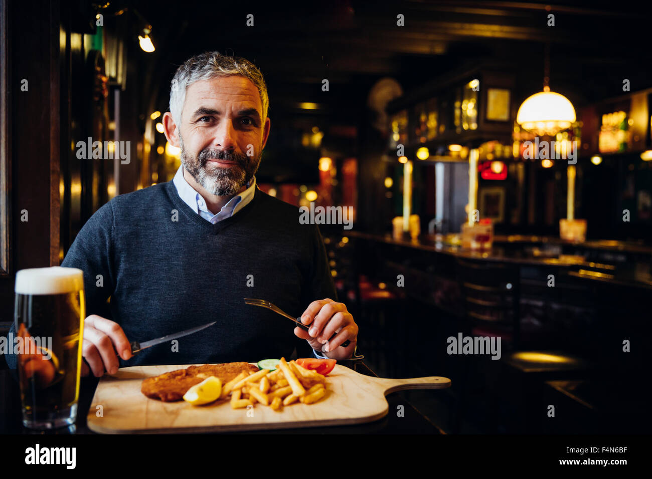 Smiling man in restaurant having Wiener Schnitzel with French fries ...