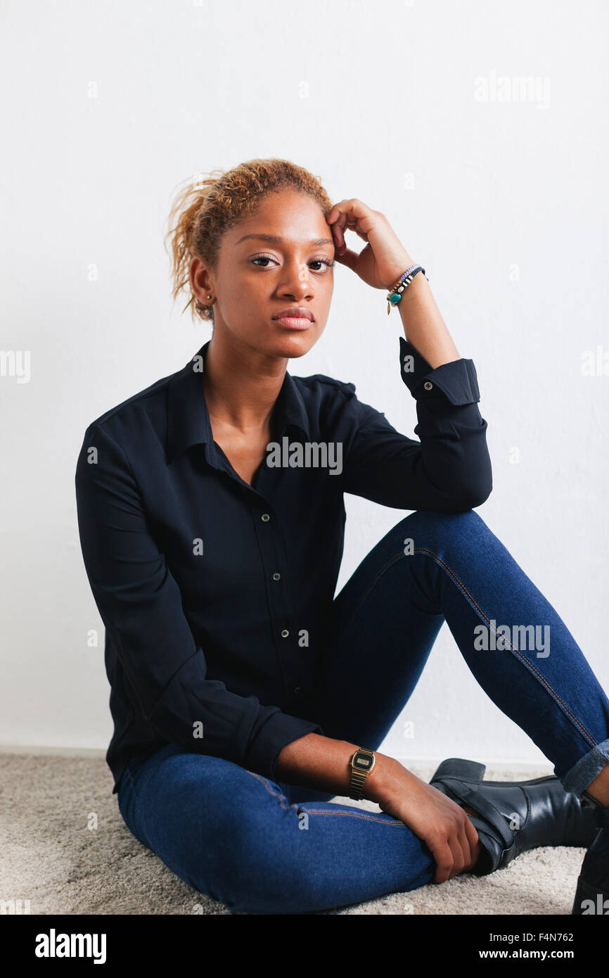 Portrait of serious looking woman sitting in front of white background ...