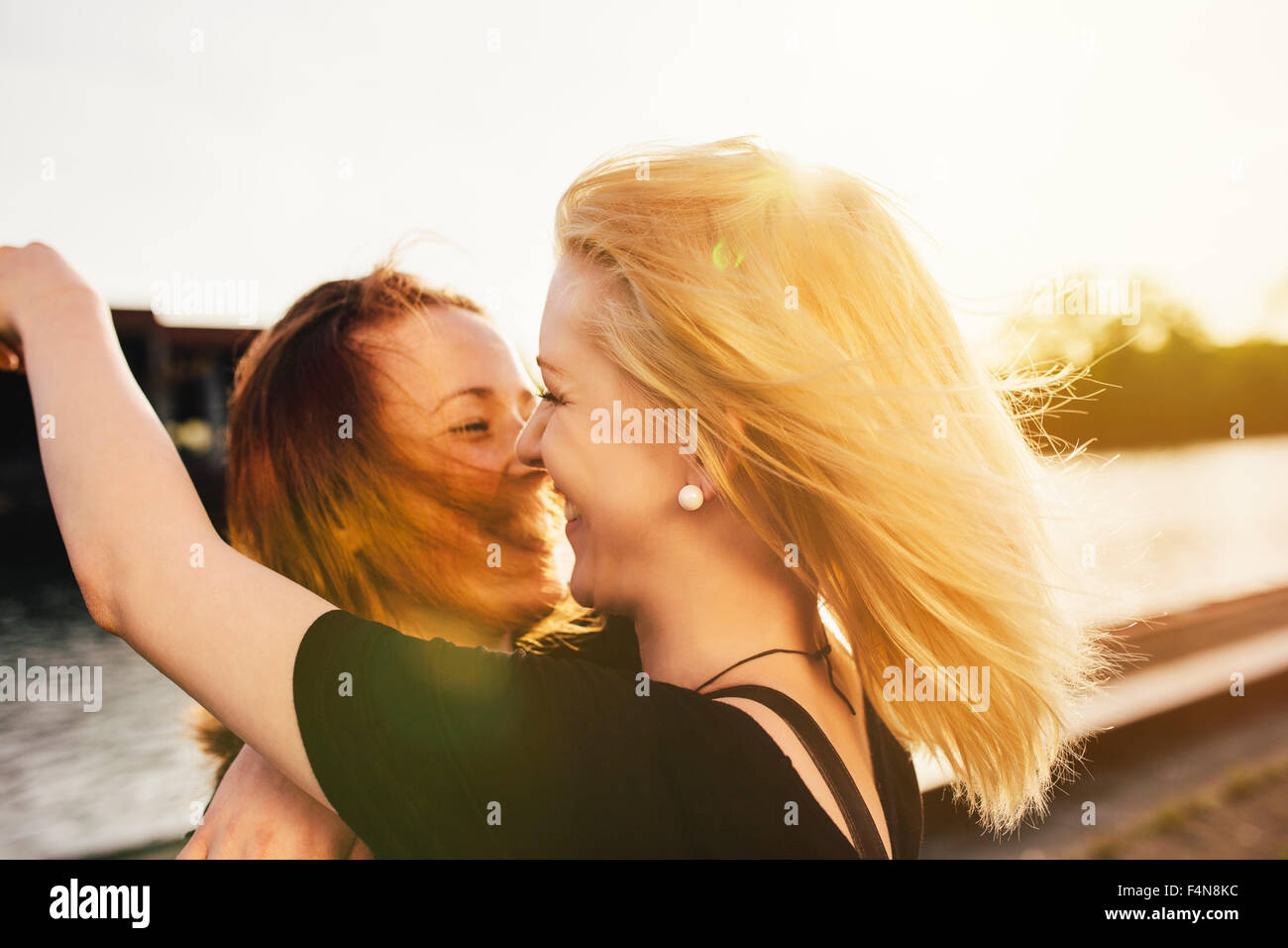 Two happy friends hugging at the waterside Stock Photo - Alamy