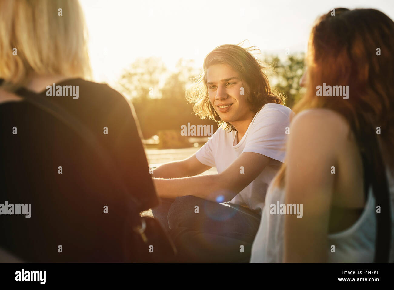 Friends sitting together outdoors at sunset Stock Photo - Alamy
