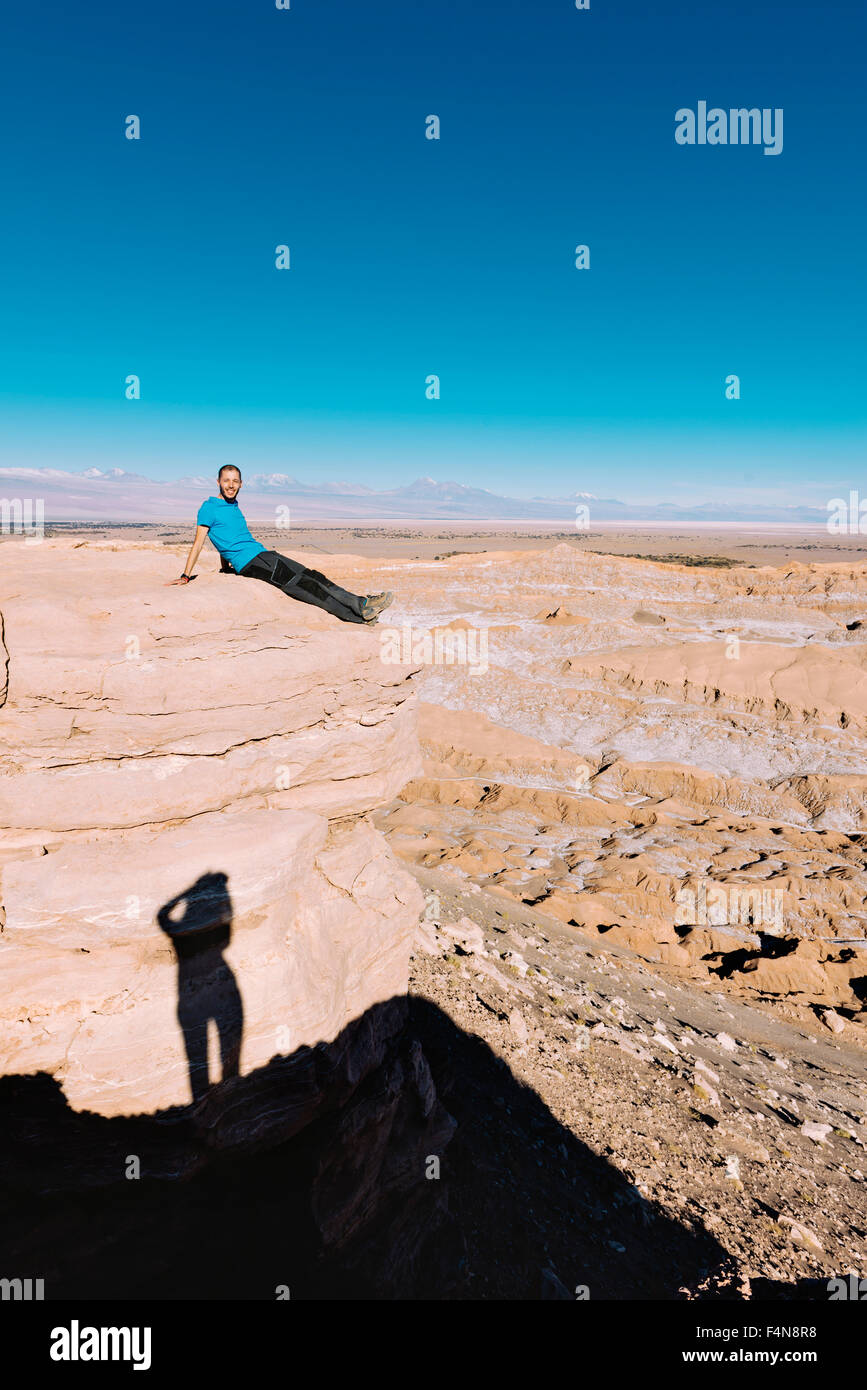 Chile, Atacama Desert, man sitting on a cliff with shadow of a ...