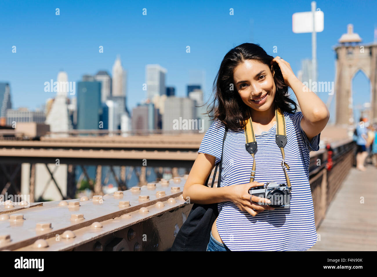 USA, New York City, portrait of smiling young woman with camera ...
