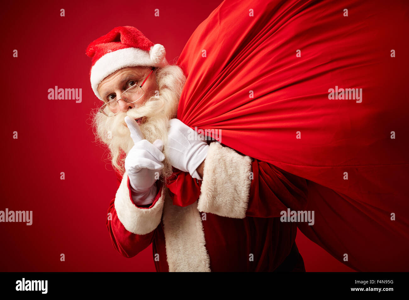 Santa showing shh gesture while carrying sack with xmas gifts Stock ...