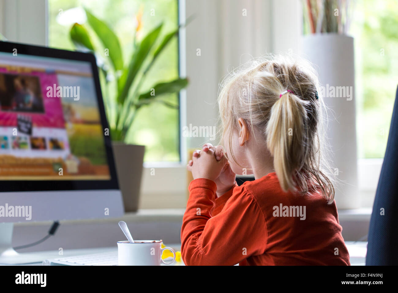 Little girl watching something on computer monitor Stock Photo - Alamy