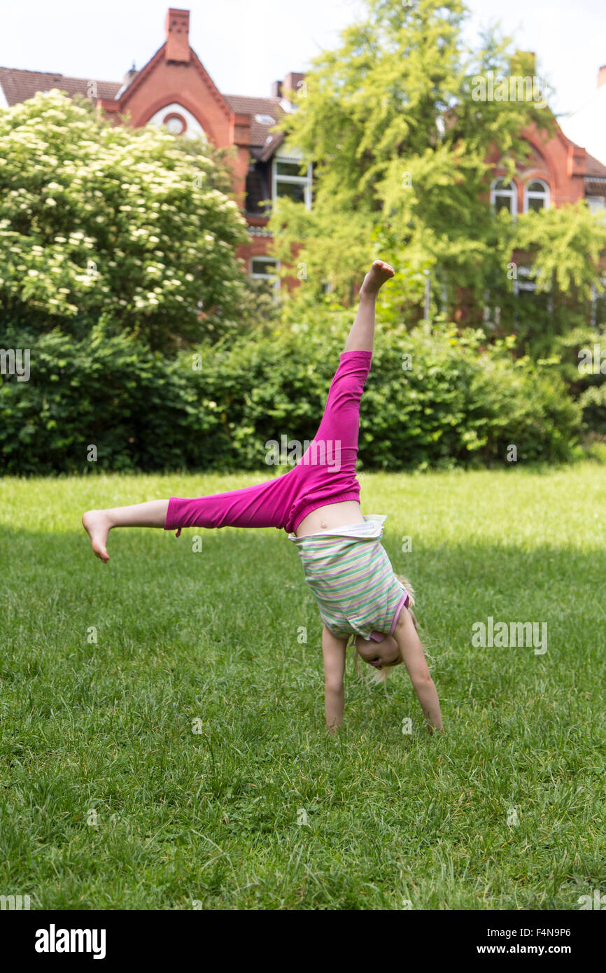 Little girl turning wheels on a meadow Stock Photo - Alamy