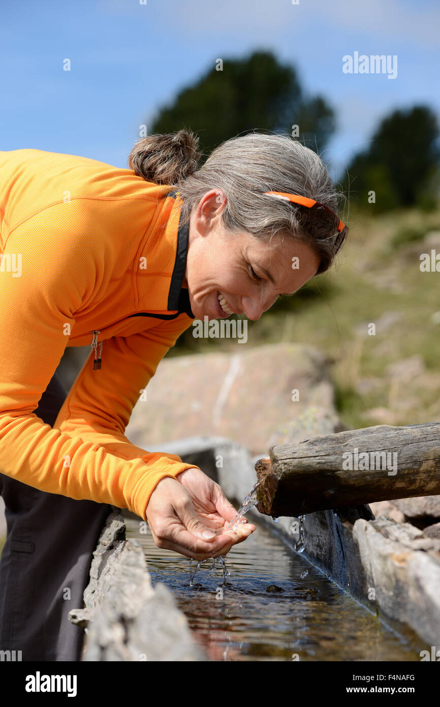 Smiling woman drinking water from a well Stock Photo - Alamy