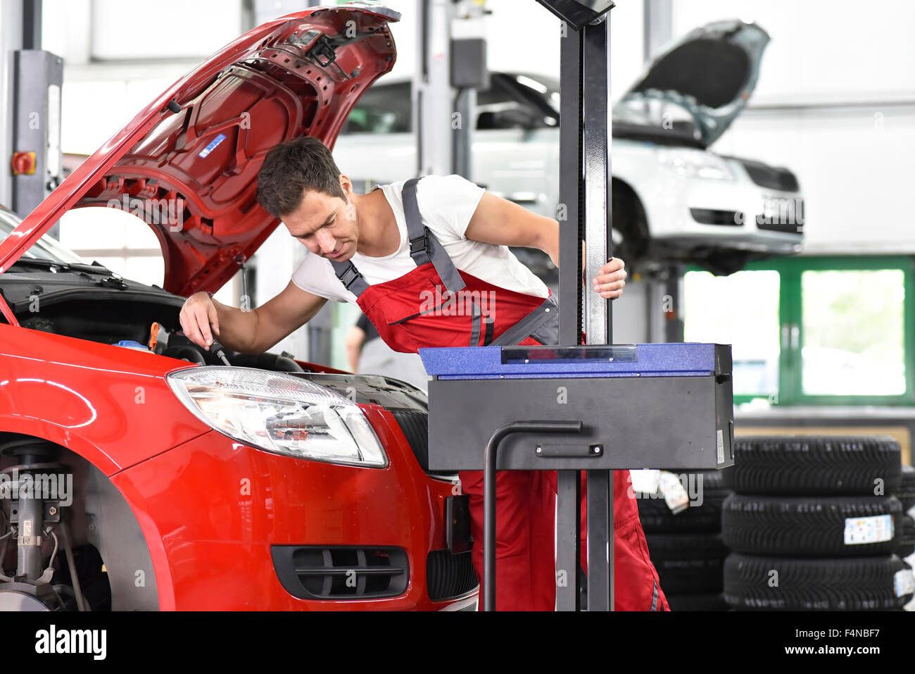 Car mechanic working in repair garage, setting car headlights Stock ...