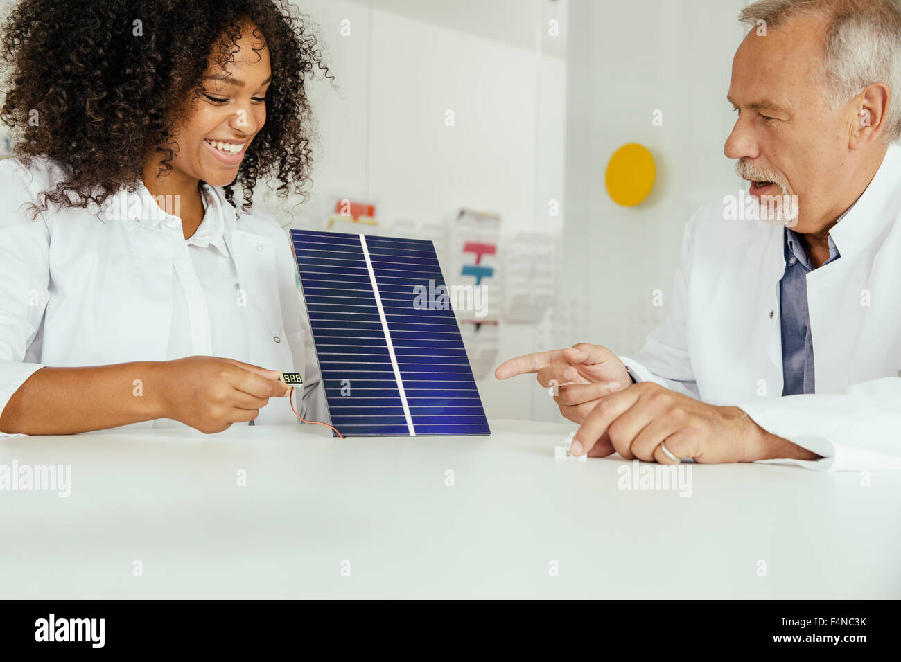 Two scientists talking about a solar panel with voltmeter in lab Stock ...