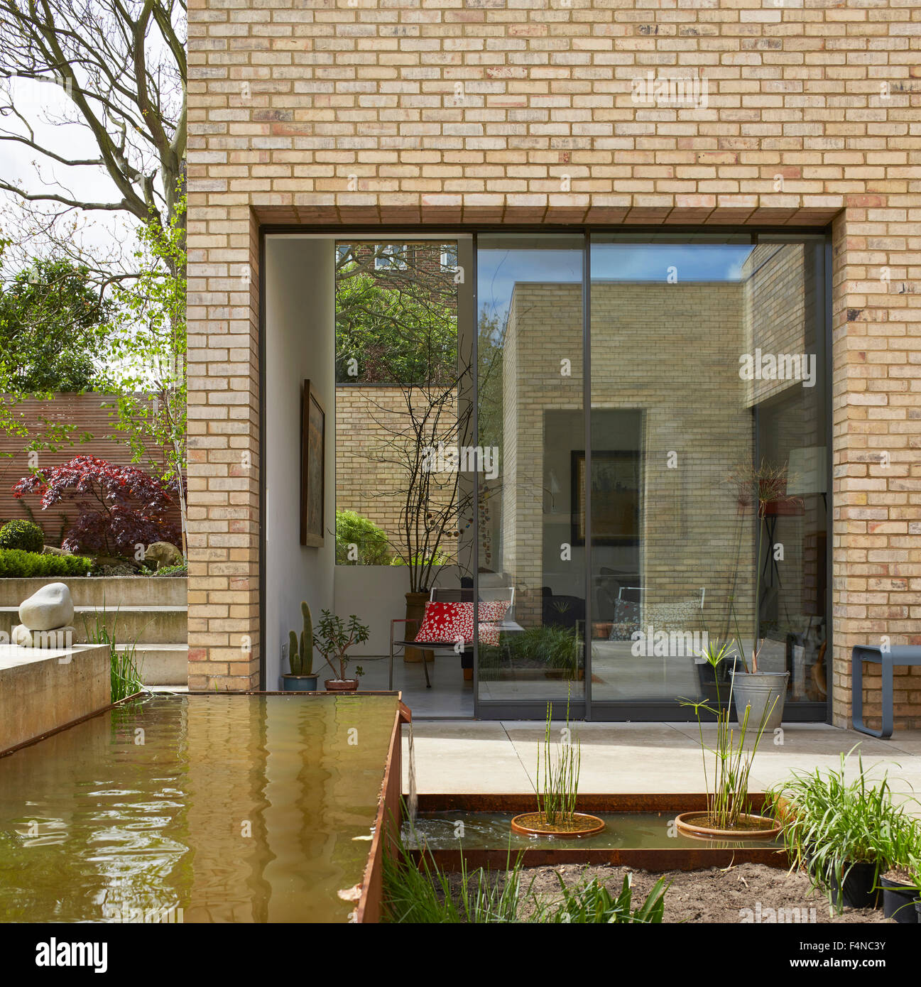 Landscaped courtyard with view towards living room. Luker House, London ...