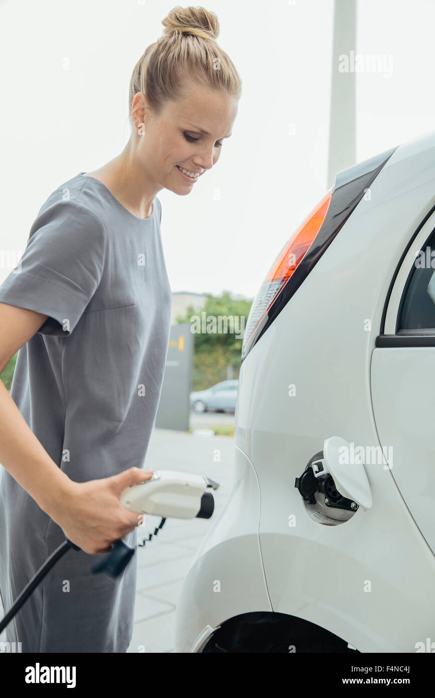 Young woman charging electric car Stock Photo - Alamy