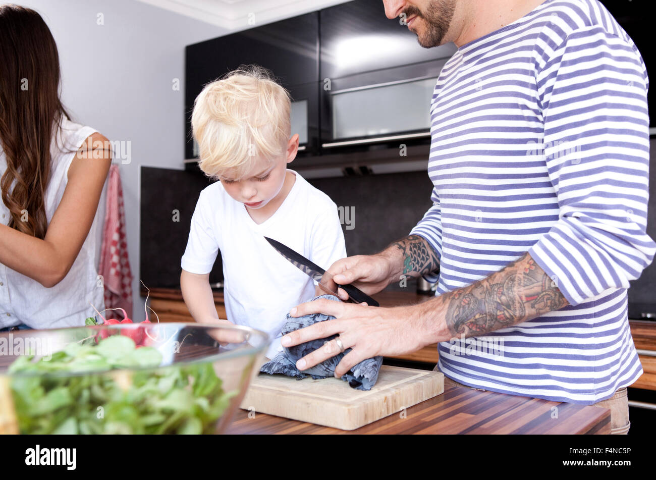 Man chopping red cabbage in the kitchen while his son watching Stock ...