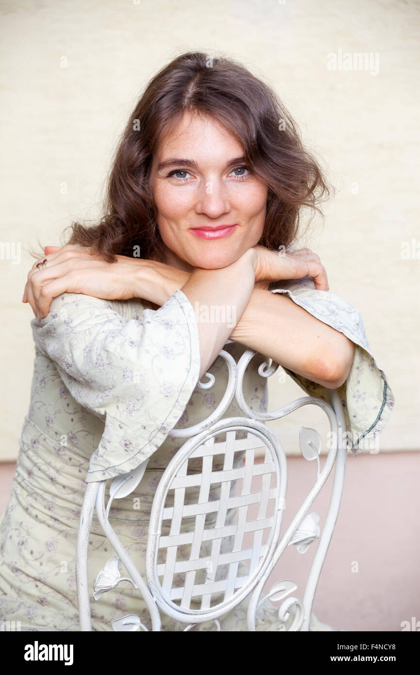 Portrait of smiling woman leaning on back rest Stock Photo - Alamy
