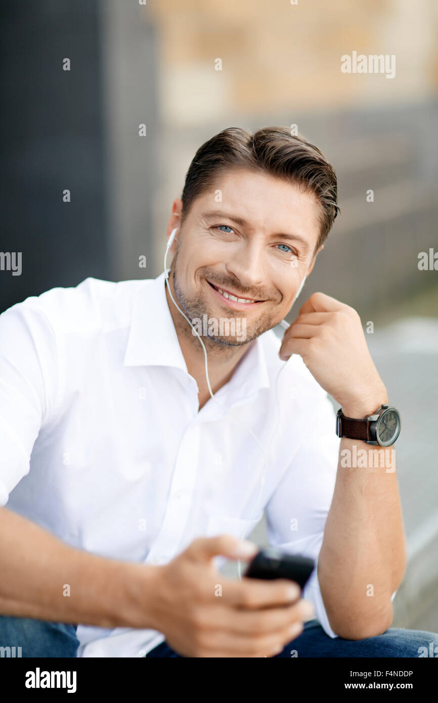 Portrait of smiling man hearing music with MP3 Player and earphones ...