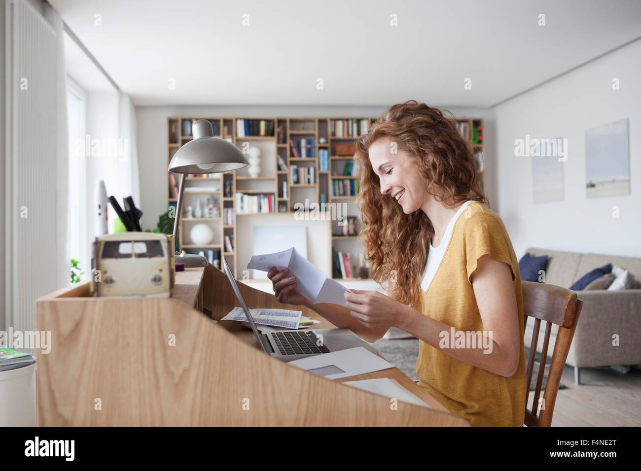 Woman at home reading letter on secretary desk Stock Photo - Alamy