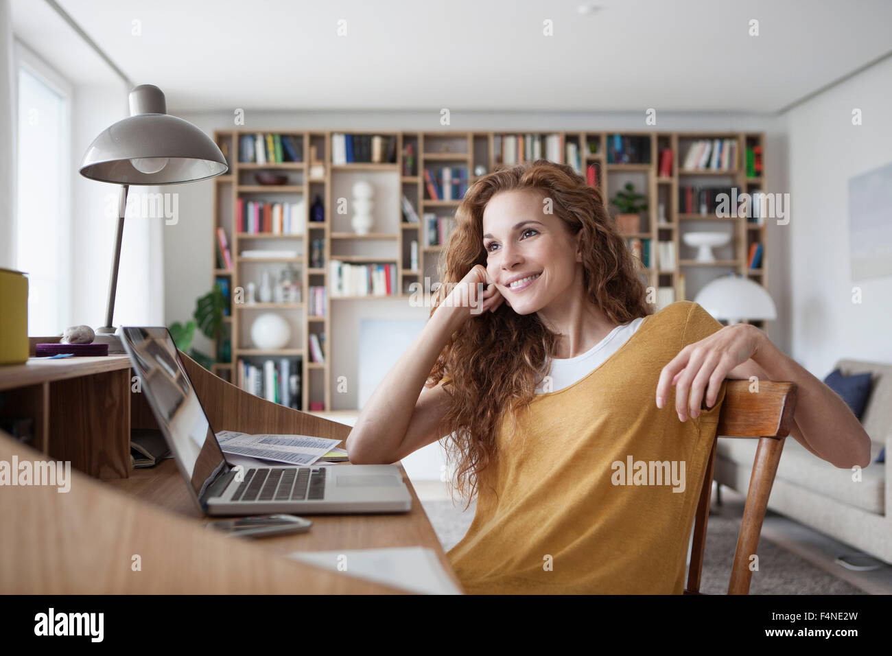 Smiling woman at home with laptop on secretary desk Stock Photo - Alamy