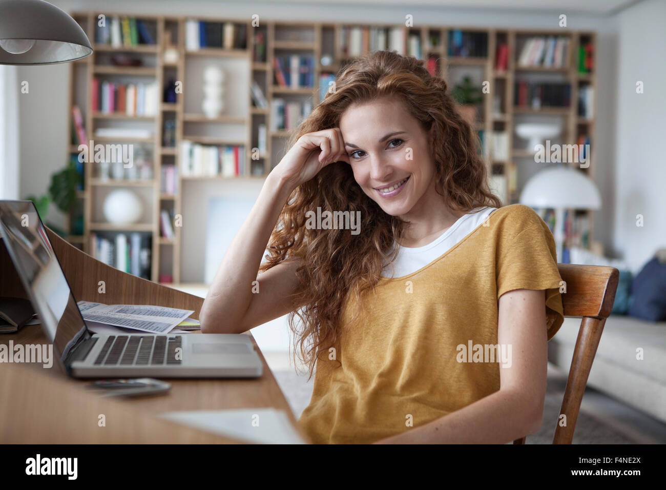 Smiling woman at home with laptop on secretary desk Stock Photo - Alamy