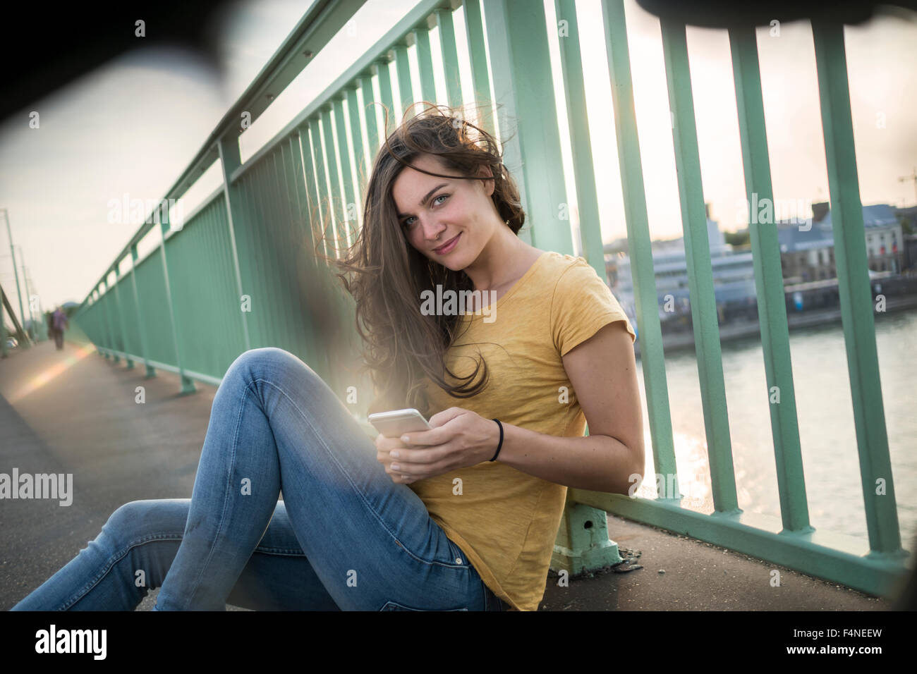 Germany, Cologne, woman sitting on Rhine bridge looking at her ...